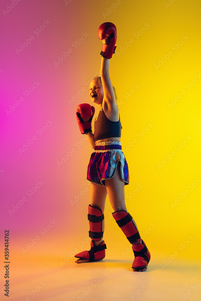 Little caucasian girl, kick boxer on gradient background in neon light ...
