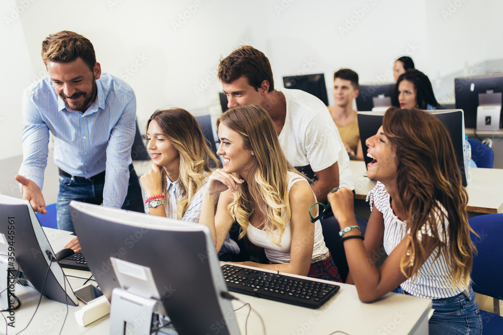 College students sitting in a classroom, using computers during class ...