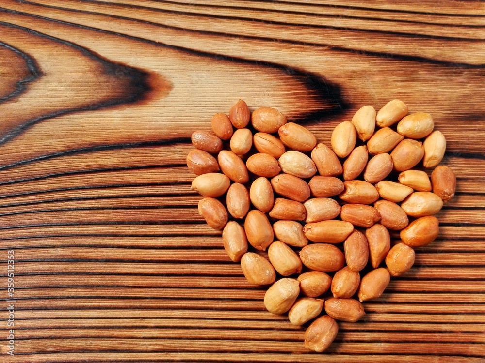 Peanut or groundnut snack heart on wood background. Closeup whole ...