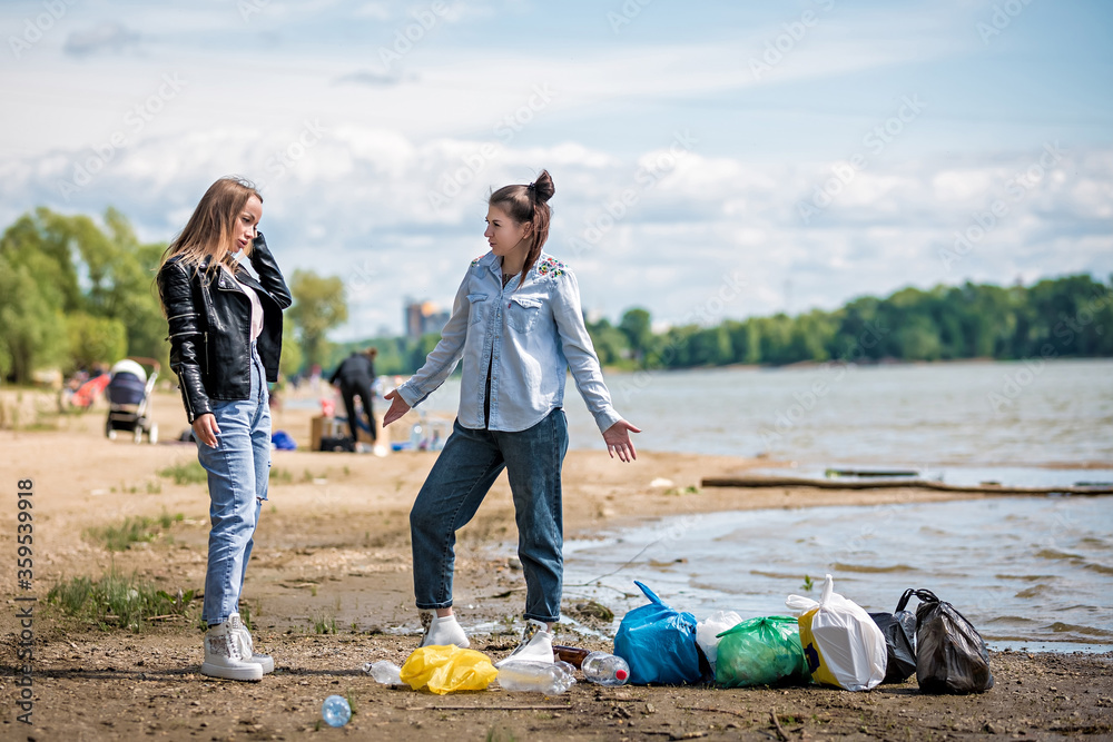 girls with trash on the beach. girls collect garbage on the beach ...