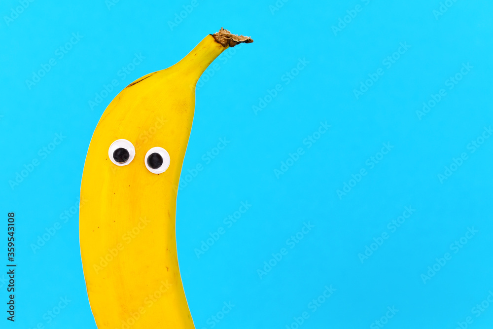 Banana fruit with funny googly eyes on bright bue background with blank ...