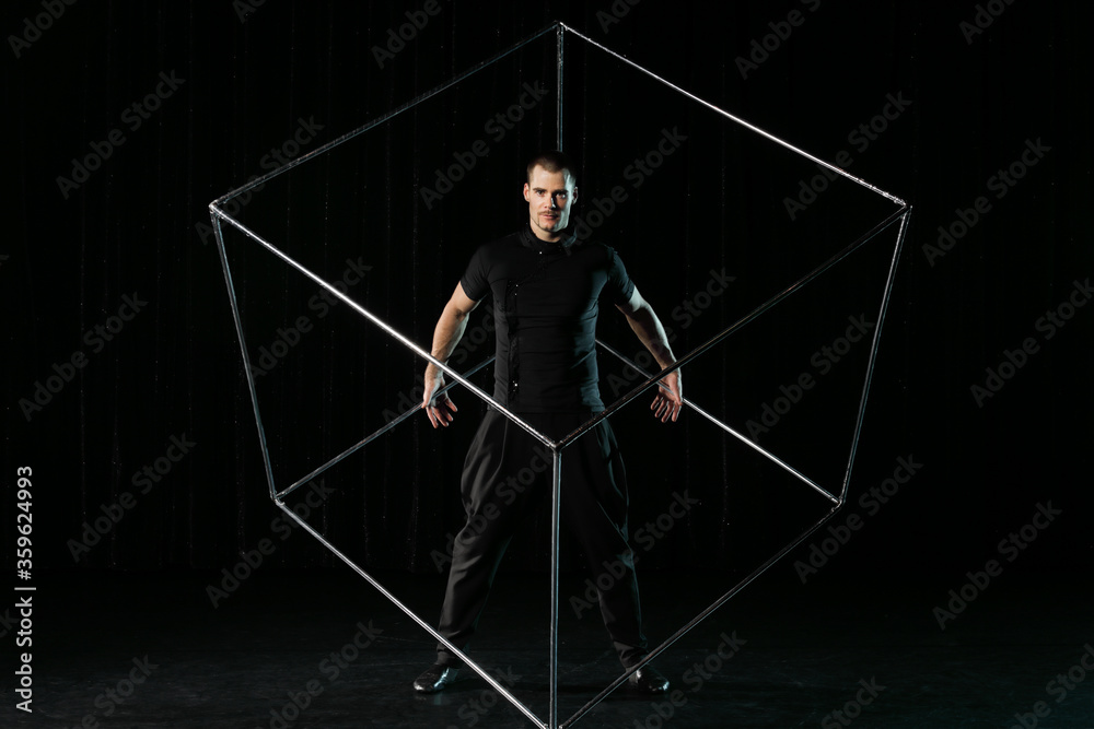 circus performer with a cube in his hands at a black background Stock ...
