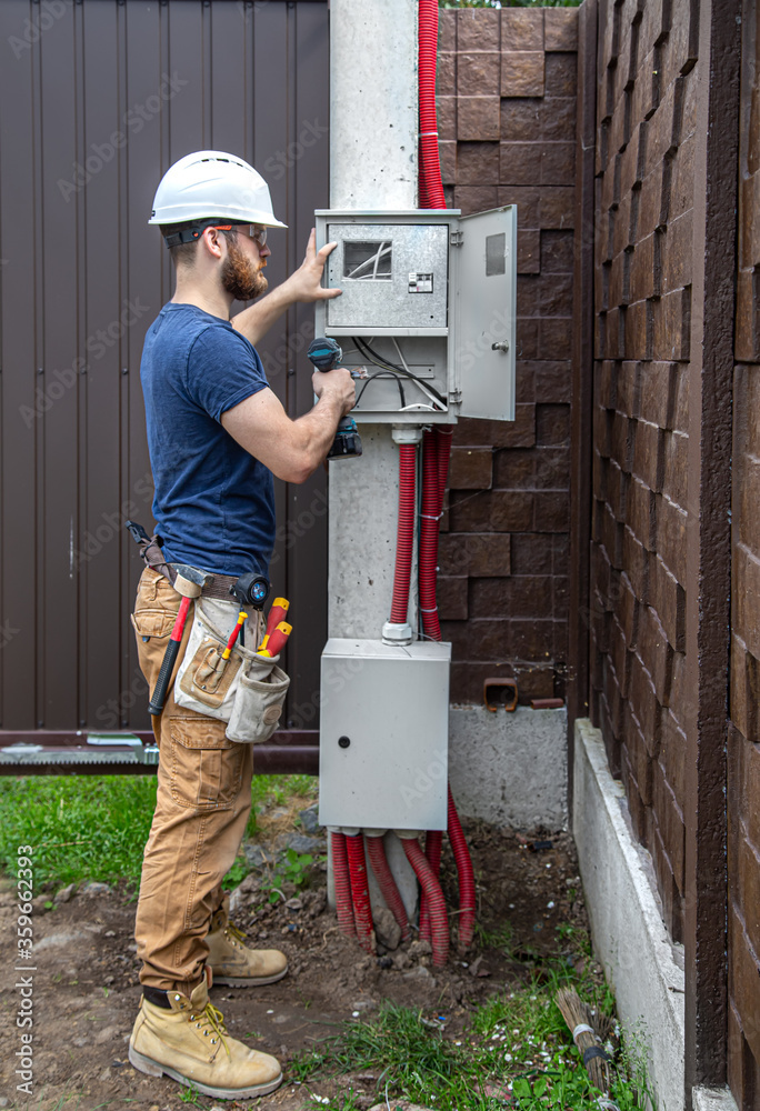 Electrician Builder at work, examines the cable connection in the ...