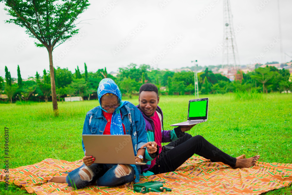 two happy africans having fun outdoors with laptop - friendship concept ...
