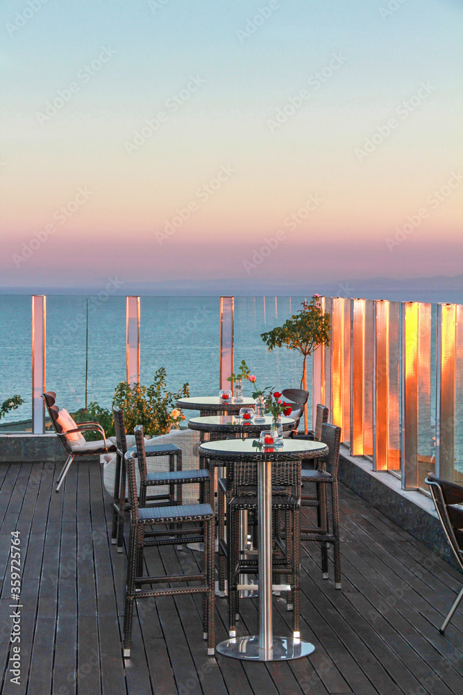 Rooftop cafe with panoramic sea views at sunset. Outdoor terrace with a ...