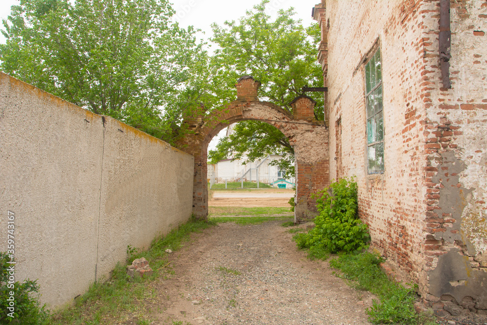 The road leads under an old brick arch with patterns above the entrance ...