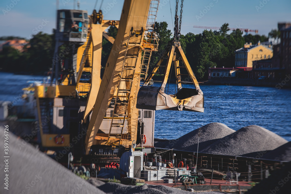 Bulk-handling crane unloading sand, road metal and gravel from cargo ...