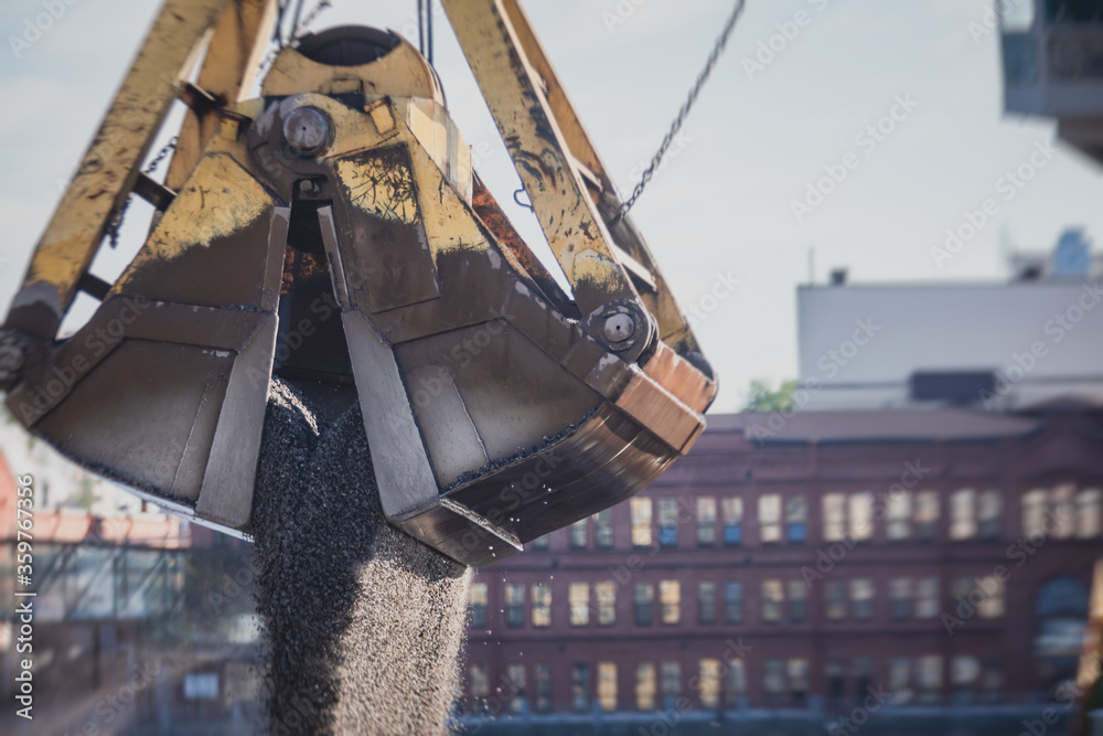 Bulk-handling crane unloading sand, road metal and gravel from cargo ...