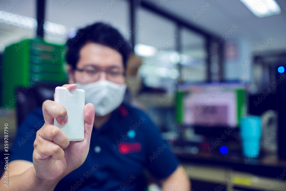 Hand is spraying alcohol with blurry businessman working in office. The ...