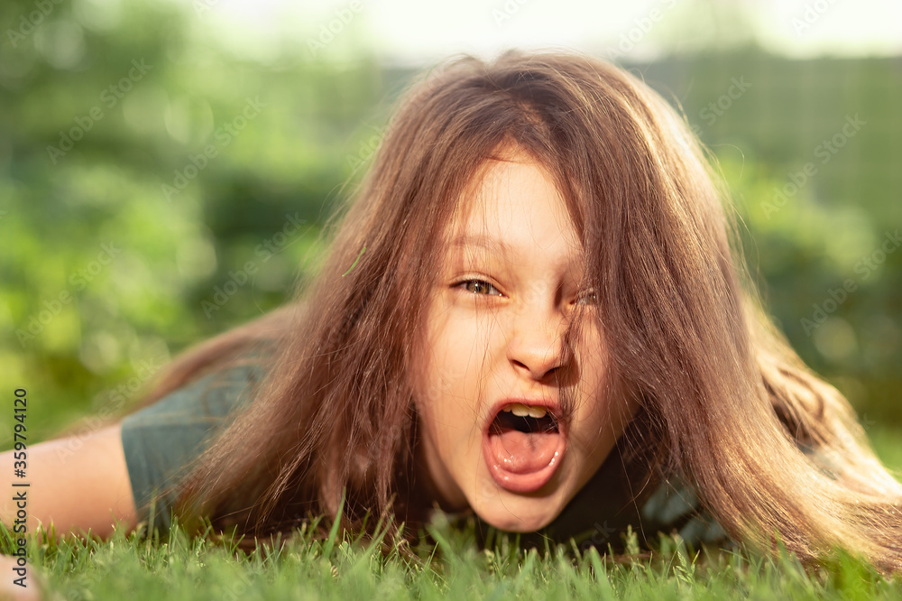 Crazy angry kid girl shouting with opened mouth and mad hair lying on ...