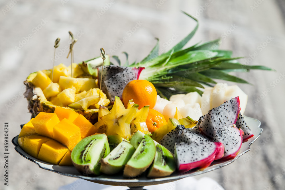 Tropical fruits laying on the dish served on the decorated table ...