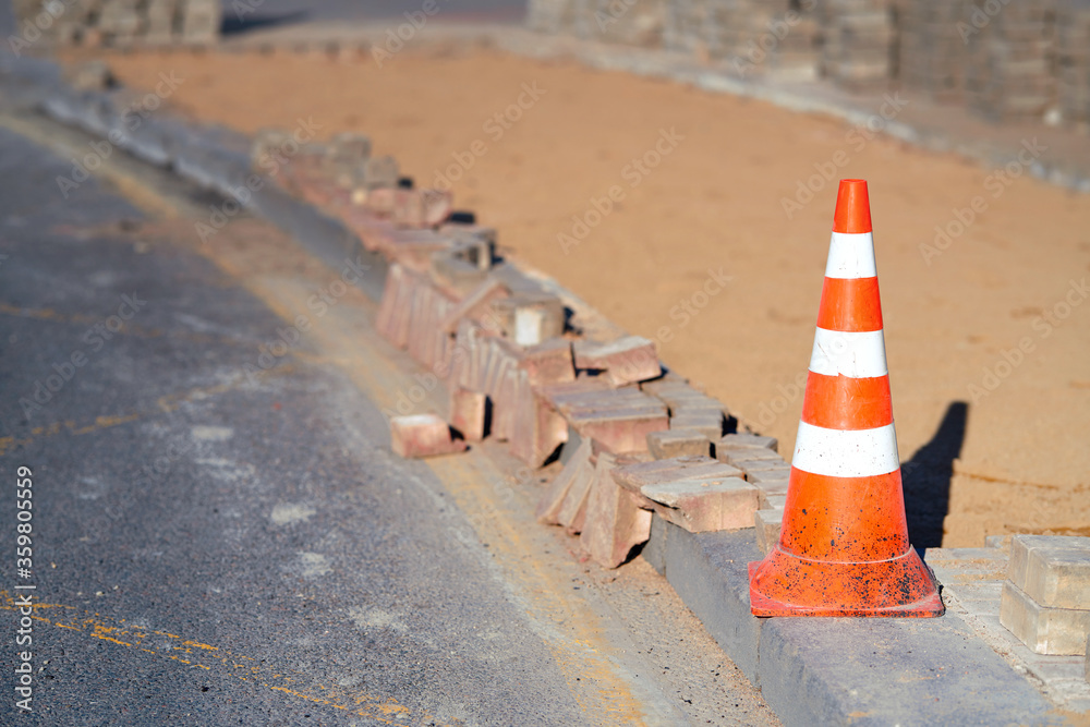 Repairing pavement and warning orange cone, laying paving slabs at ...
