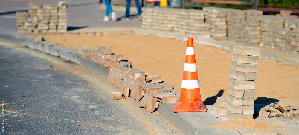 Repairing pavement and warning orange cone, laying paving slabs at ...