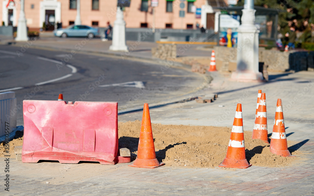 Repairing pavement and warning orange cone, laying paving slabs at ...
