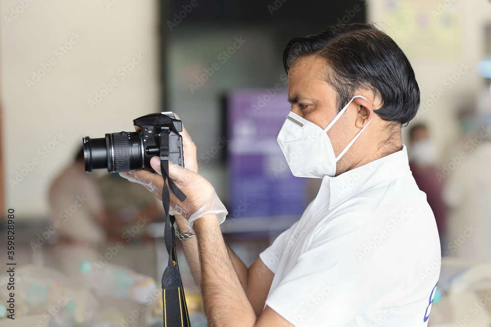 Photographer at work during Covid-19 pandemic. Photographer in mask and ...
