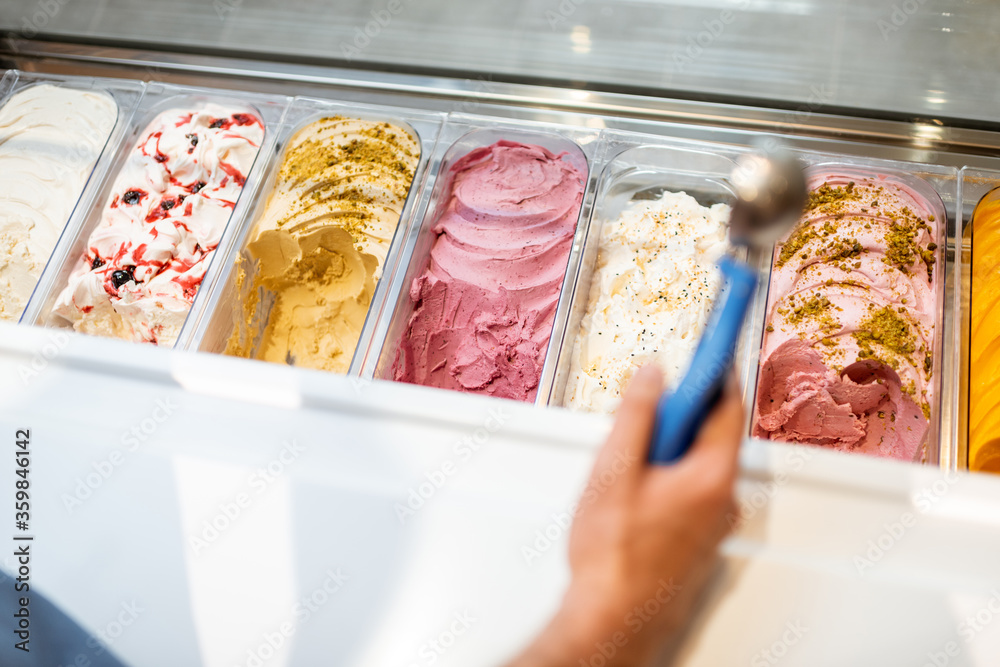 Salesman picking ice cream with a spoon from refrigerator in the store ...