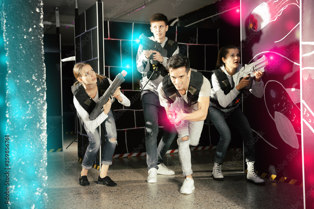 Cheerful Laser tag players young mens and womens playing in teams in ...