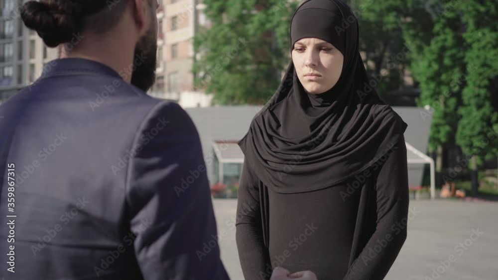 Portrait of stressed young muslim woman listening to unrecognizable ...