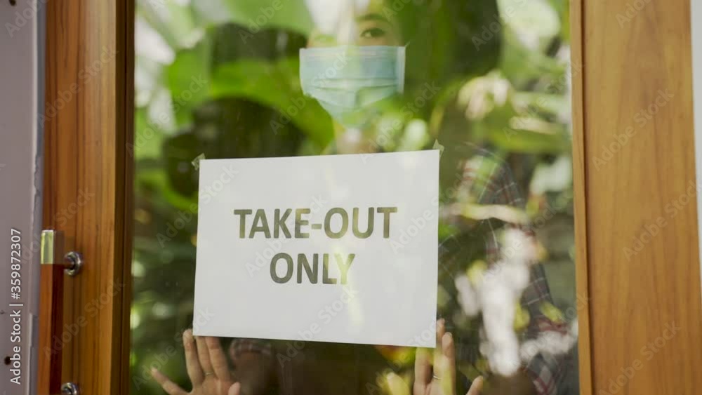 coffee shop owner sticking sign on the front door. take out only sign ...