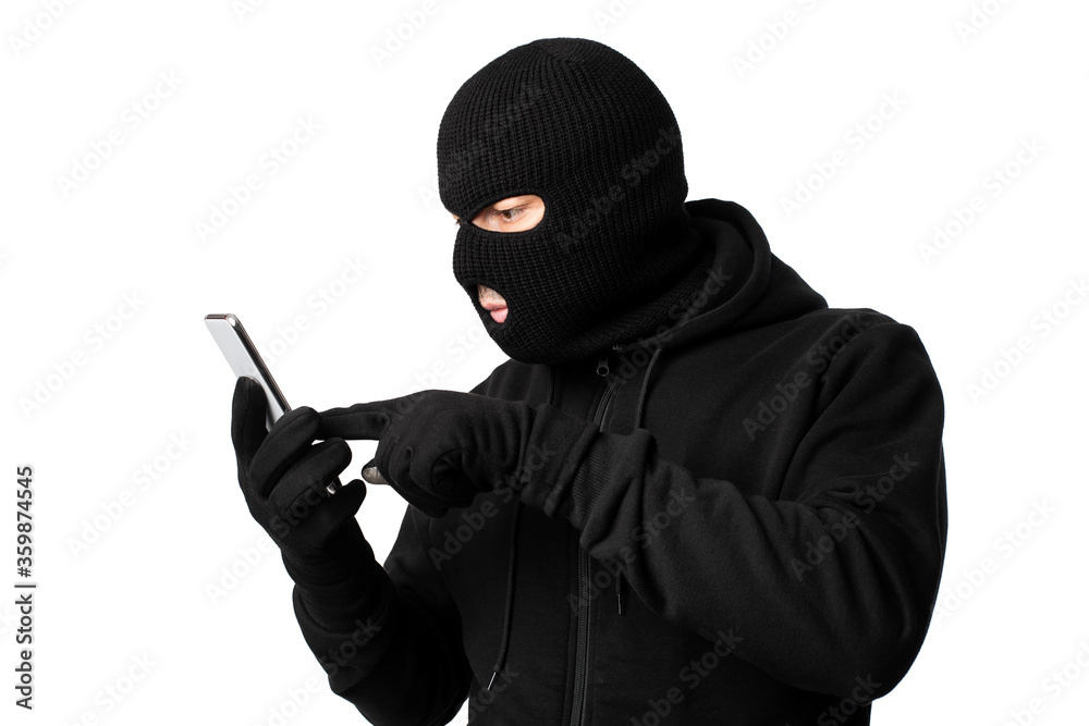 Masked villain touching a smart phone screen Stock Photo | Adobe Stock
