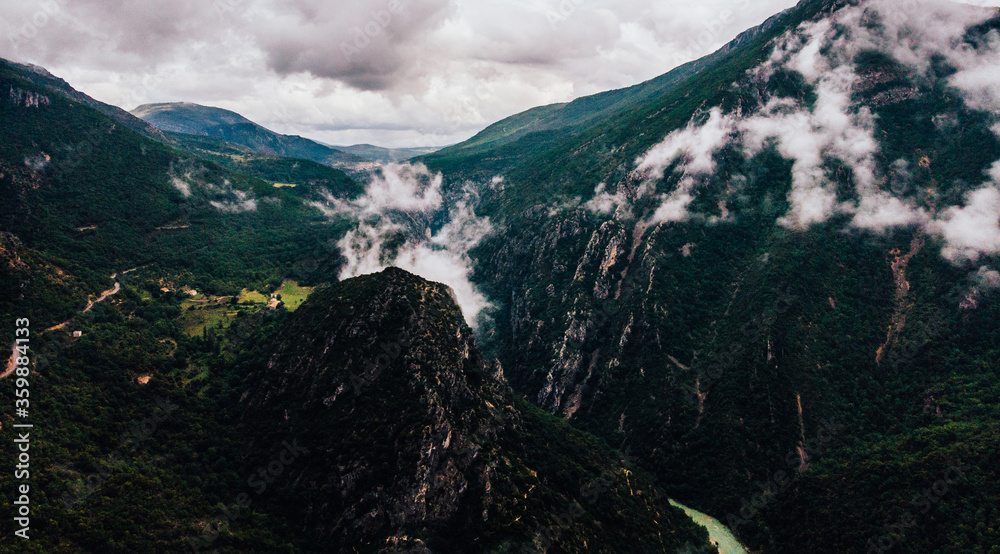 Aerial scenery view of rocky mountains with green vegetation covered with fog after rain. Bird's ...