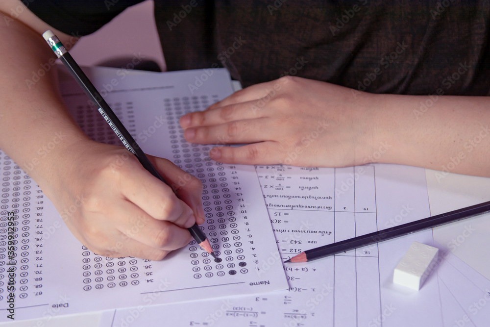 Students hand holding pencil writing selected choice on answer sheets ...