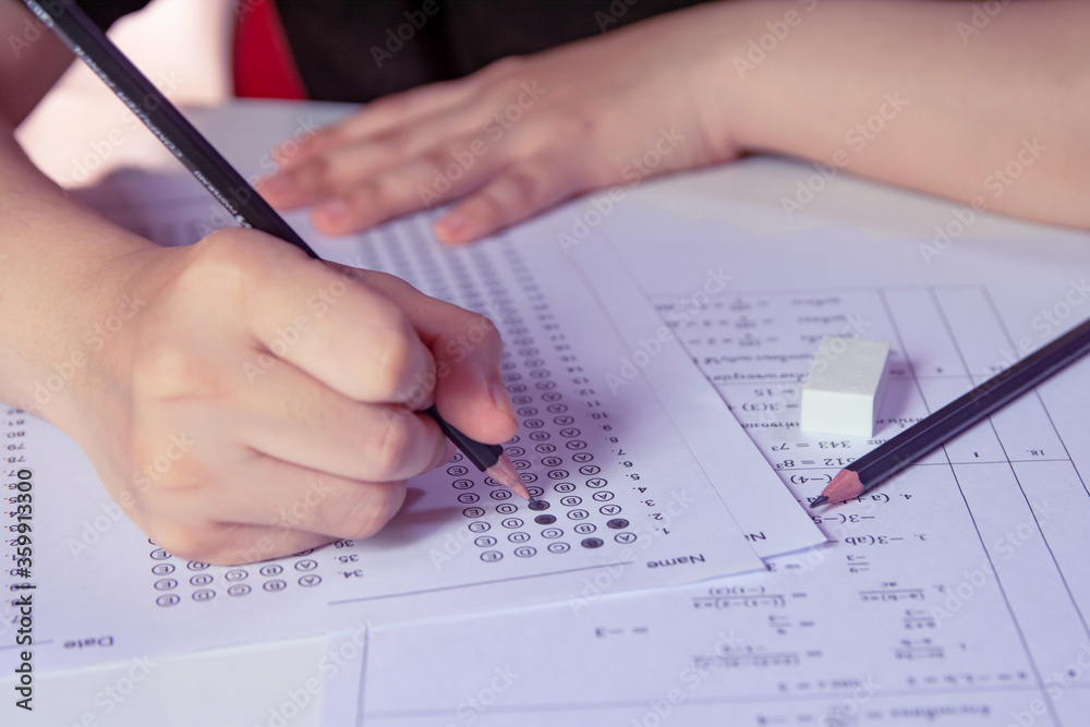 Students hand holding pencil writing selected choice on answer sheets ...