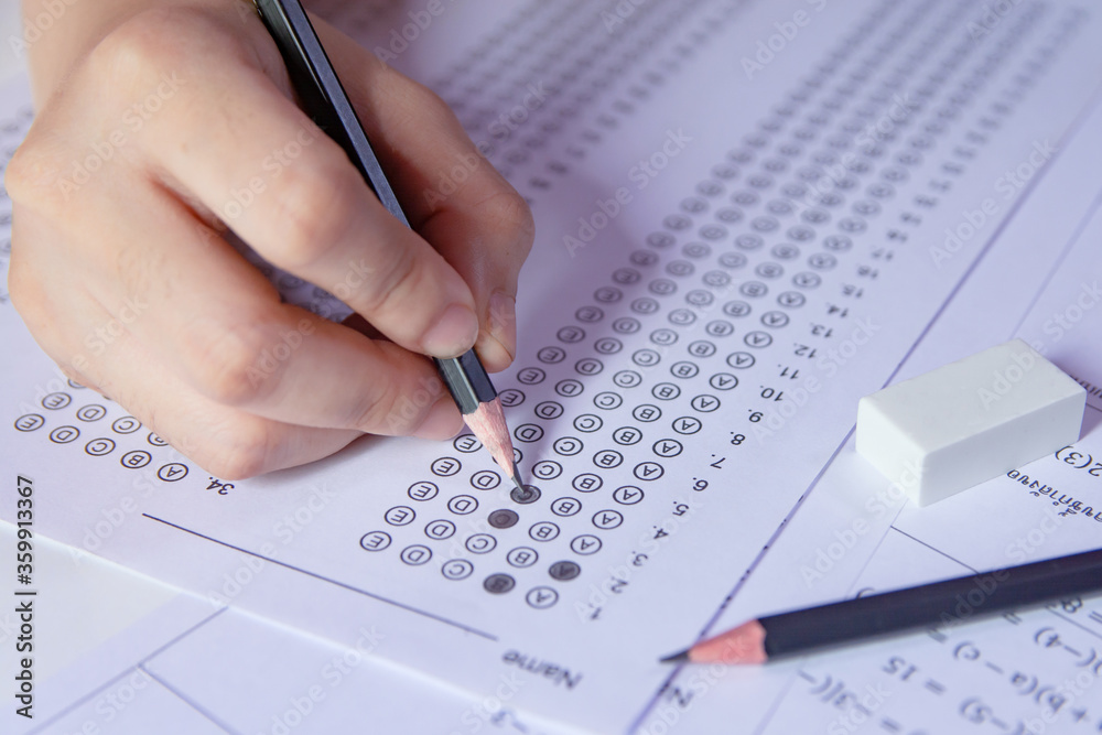 Students hand holding pencil writing selected choice on answer sheets ...