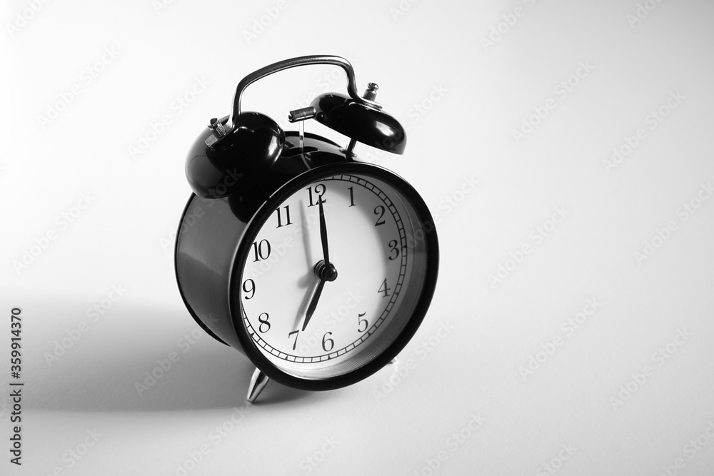 Black vintage alarm clock on table. White background. Wake up concept ...