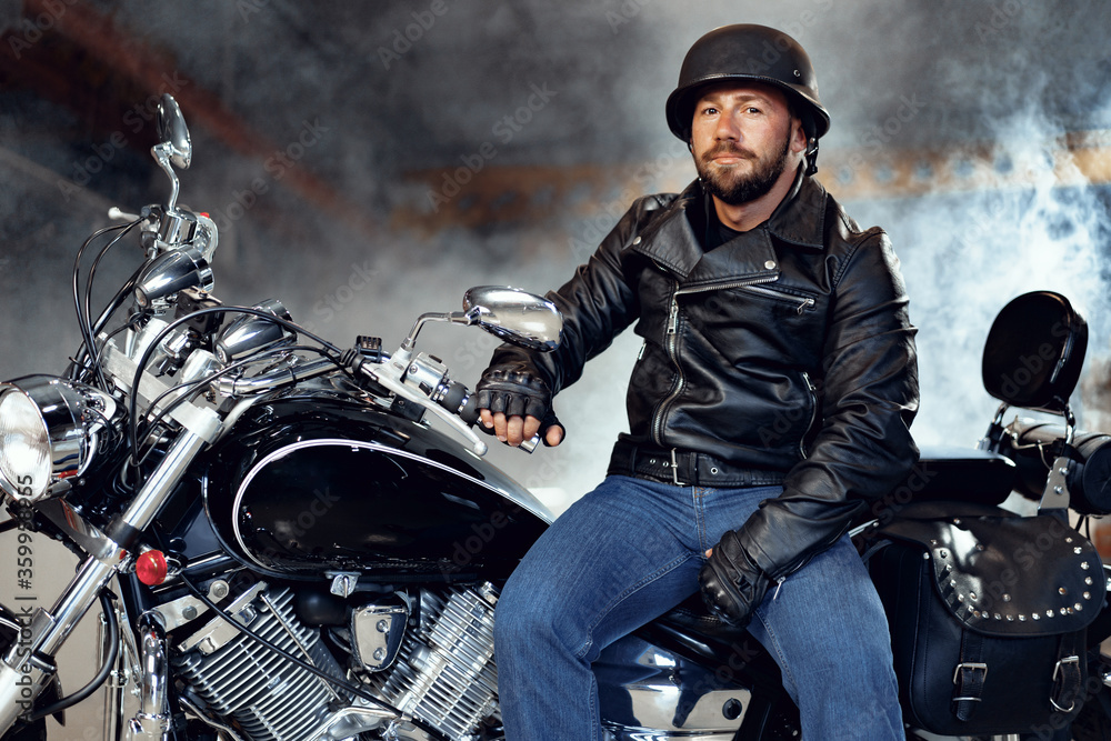 Biker man in leather jacket and helmet sitting on his motorcycle Stock ...