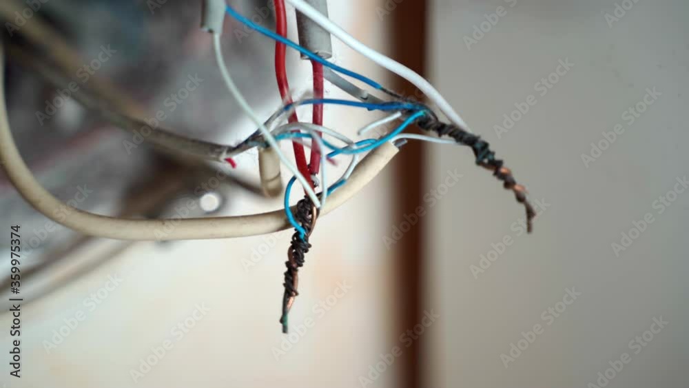 White, blue and red electrical wires twisted with black insulting tape ...