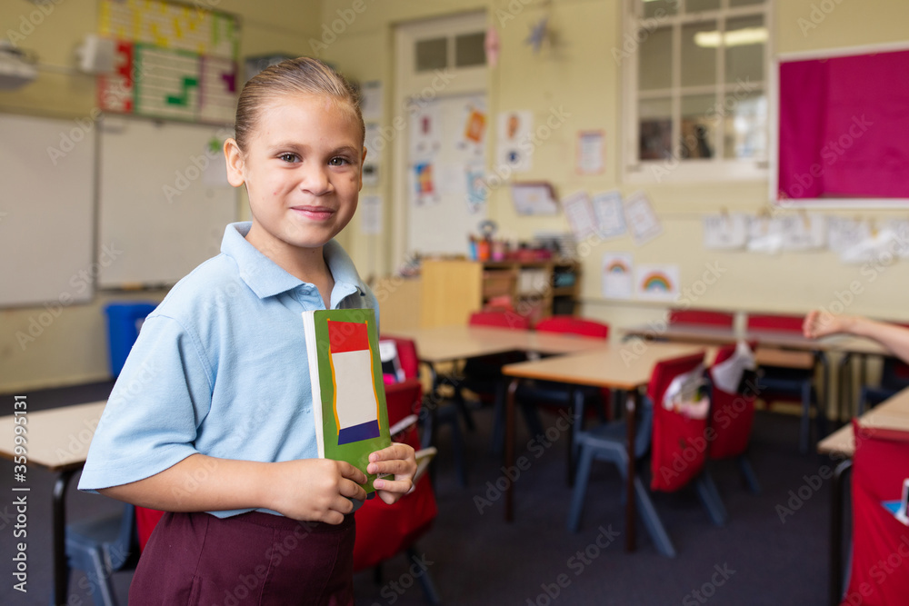 Indigenous primary school girl student holding books smiling in a ...