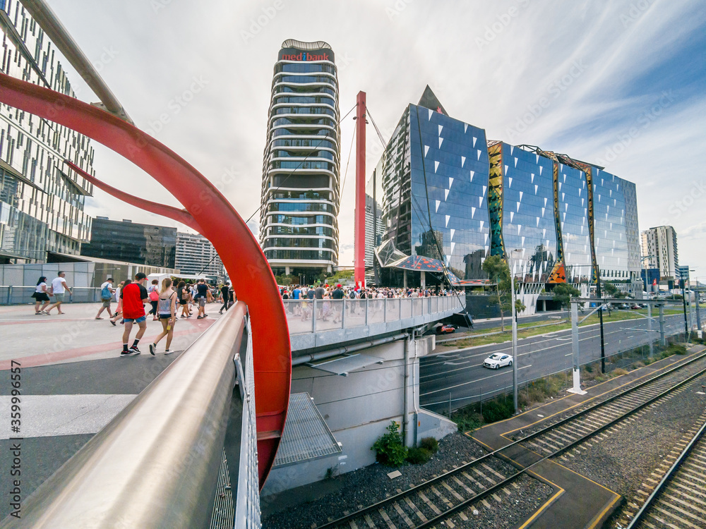 People walking on a transit bridge over roads and railway lines towards ...
