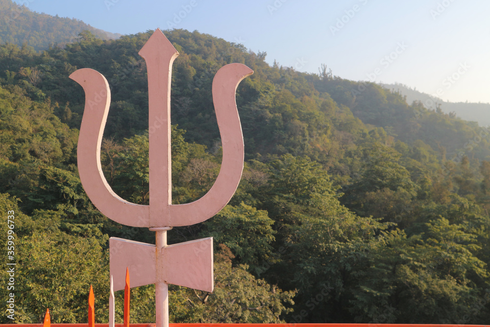 The symbol of Lord Shiva is the trishula trident against the backdrop of mountains in Rishikesh ...