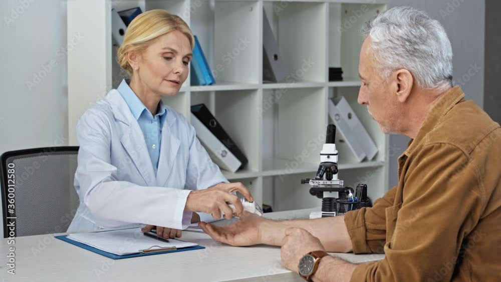 middle aged doctor using pyrometer on man and writing diagnosis Stock ...