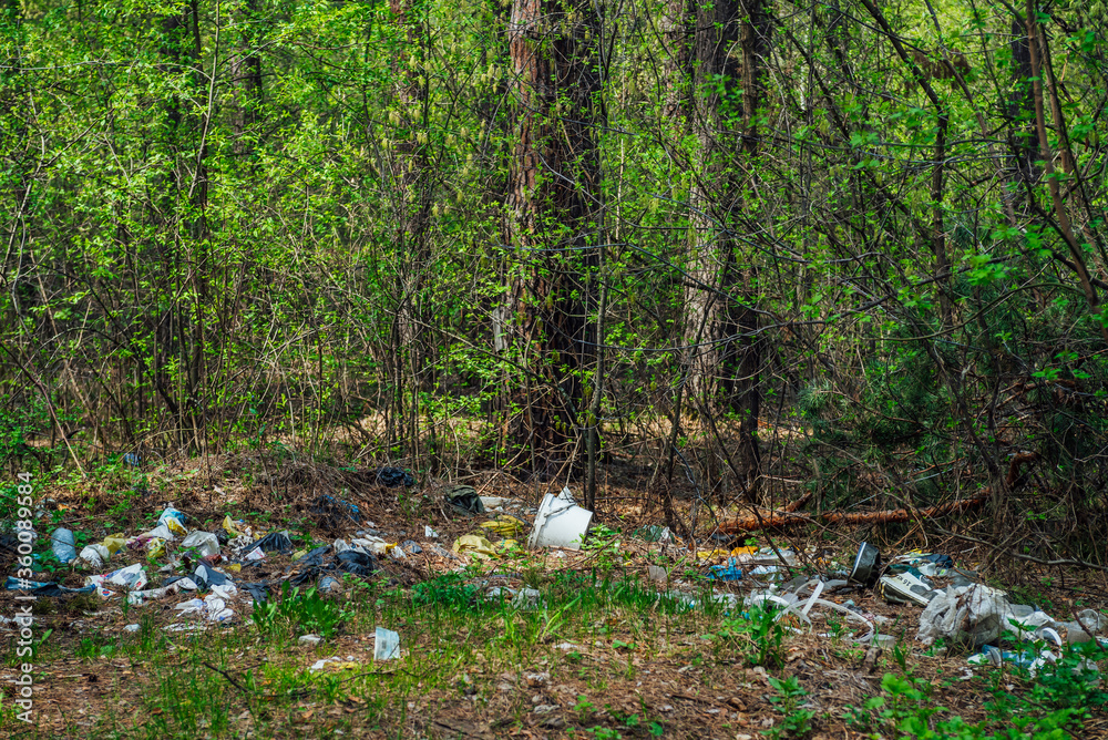Garbage pile in forest among plants. Toxic plastic into nature ...
