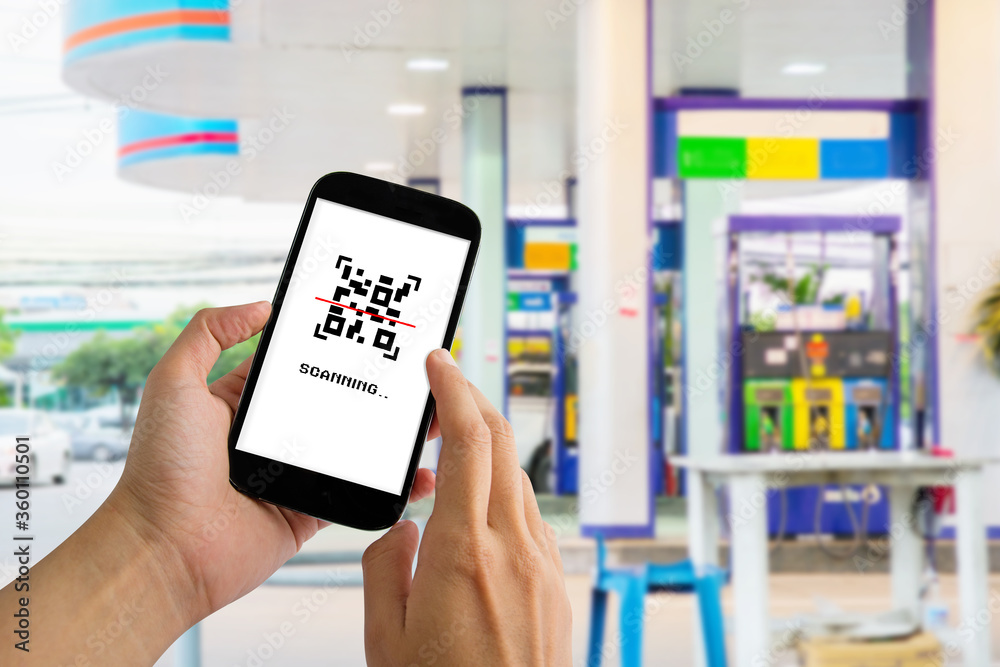 Man use smartphone scanning QR code for make a payment for refueling ...