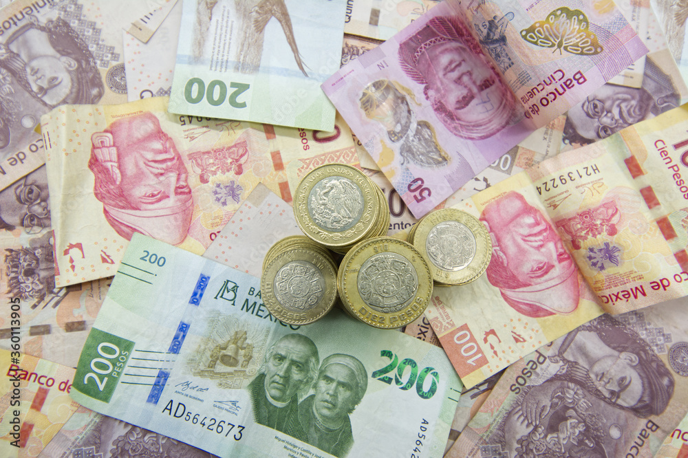 Ten pesos coins on bills of different denominations of Mexican pesos ...