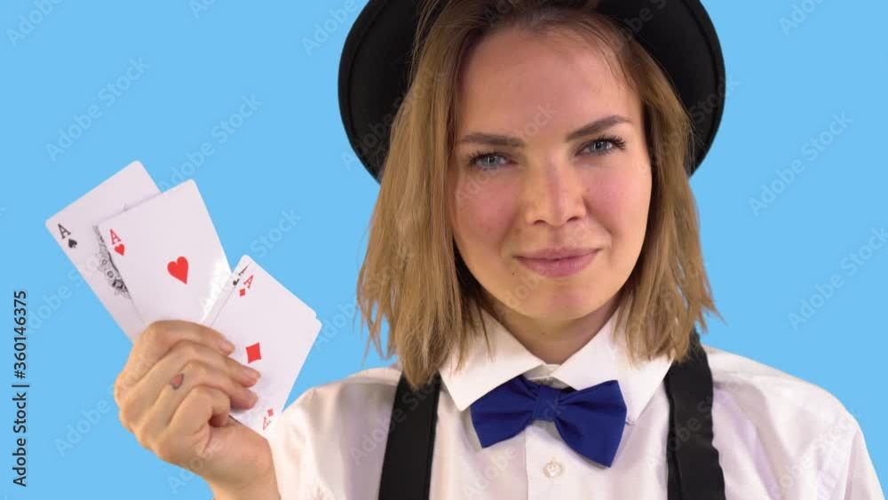 Croupier girl in a white shirt and hat and bow-tie shows playing cards ...