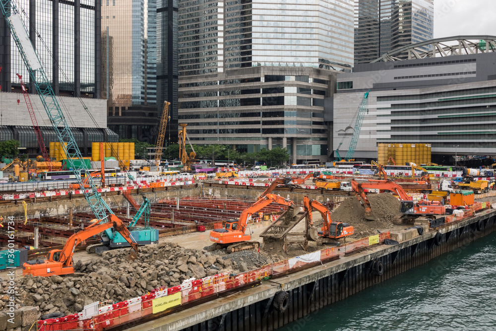 Construction site surrounded by skyscrapers in a big city. Excavators ...