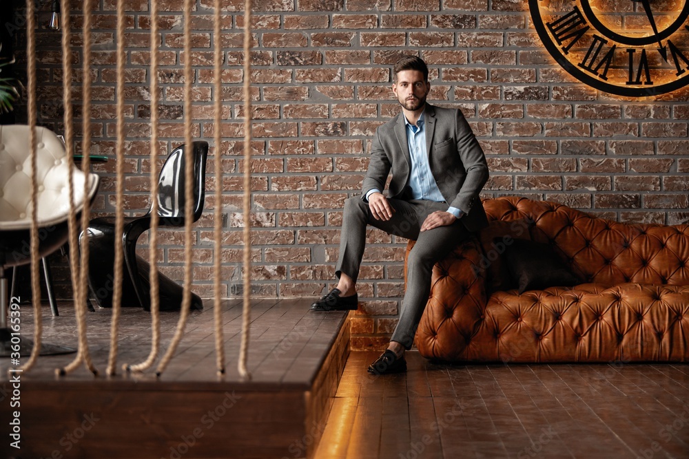 Cool and handsome. Good looking young man in full suit sitting on the ...