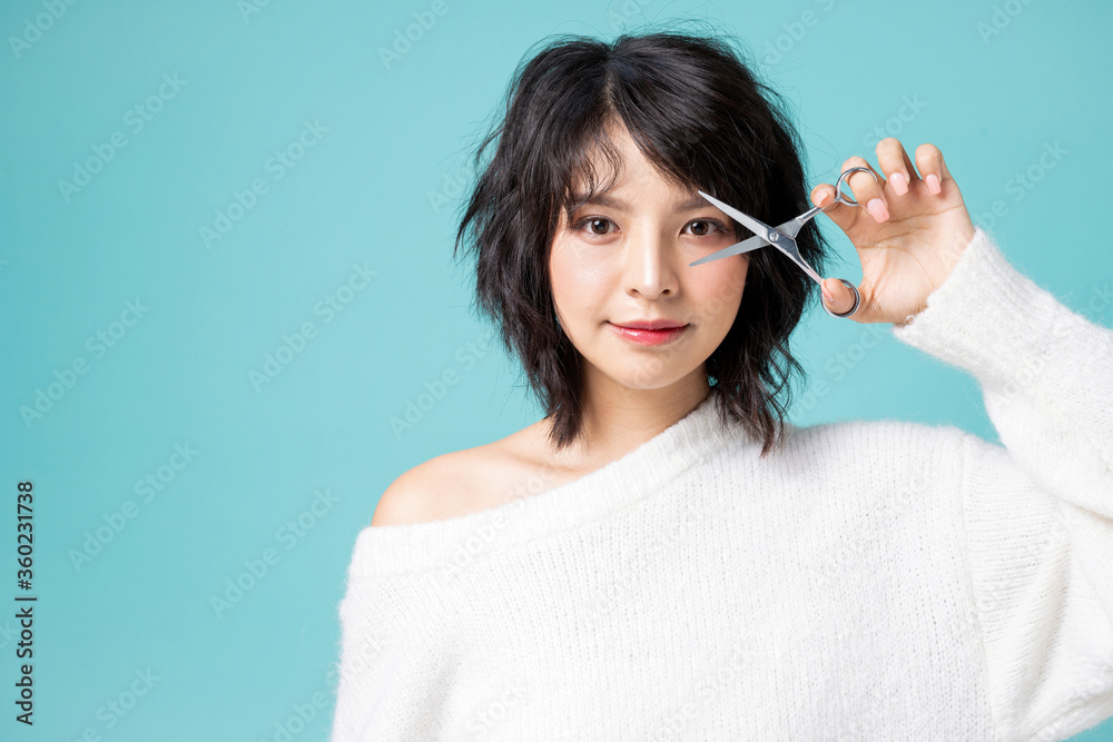 Young Asian woman cutting her bangs by herself isolated image on light ...