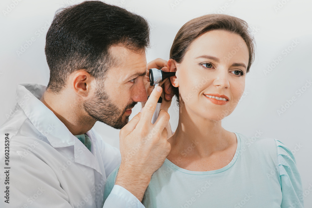 ENT doctor doing an ear exam with an otoscope to a woman patient ...