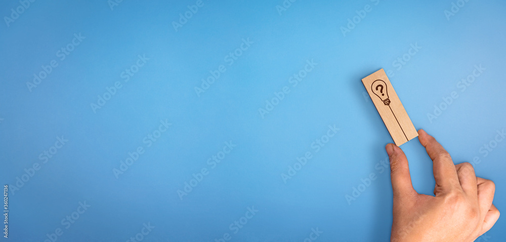 Question mark concept. Hand holding a wooden block with bulb and ...