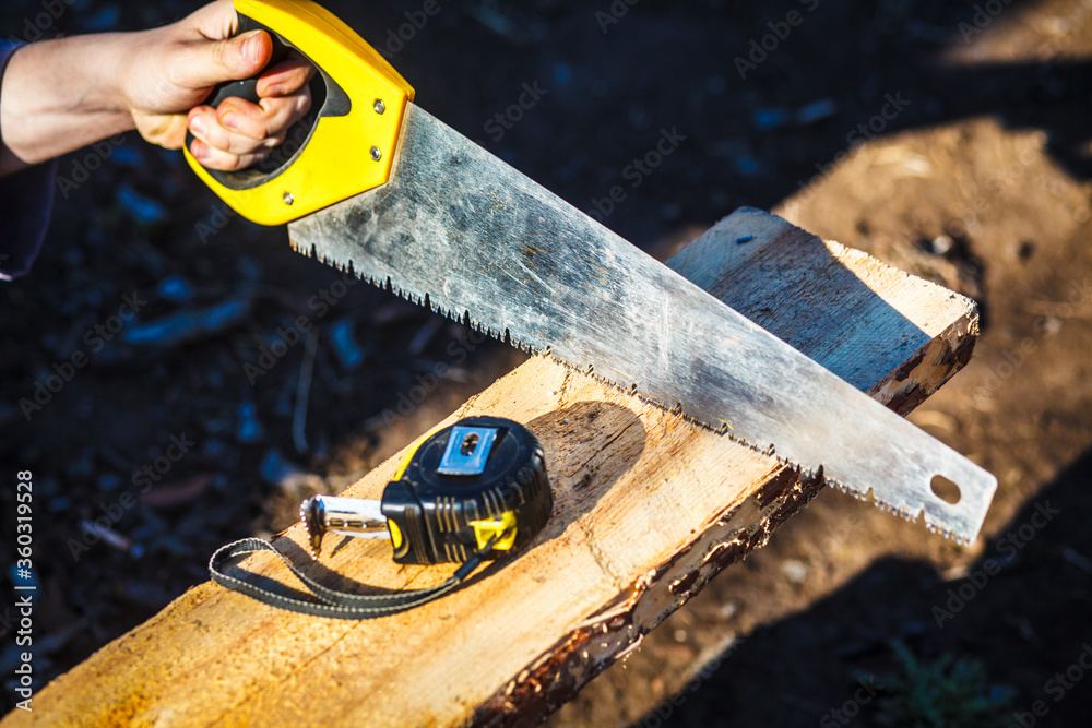Saw with a construction tape measure on wooden board. Wooden plank ...