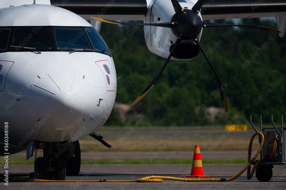 Closeup of a nose cone and a wing of a turboprop aircraft parked on a ...