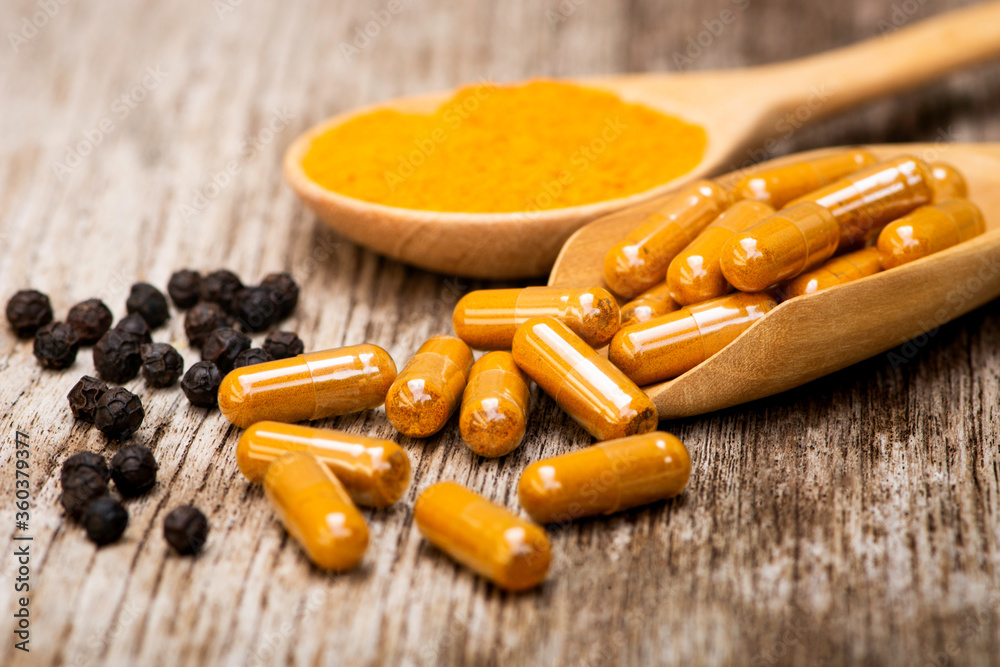 Curcuma capsules and Curcumin powderin wooden spoon and black ...