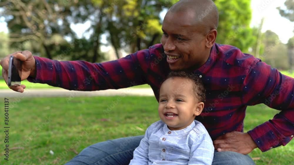 African American bald father making selfie with cute son. Dad sitting ...