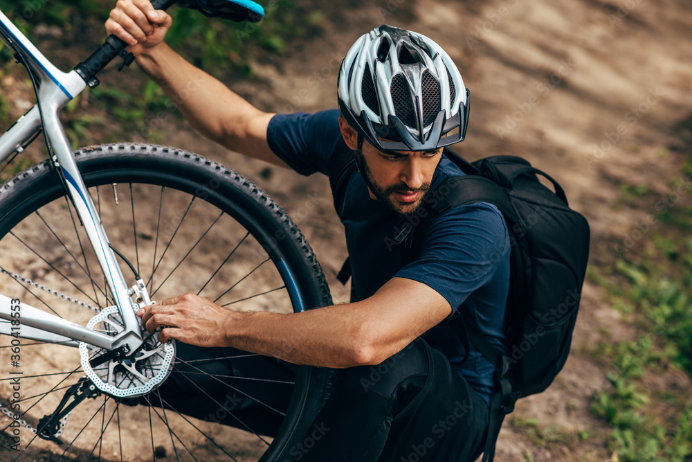 Outdoor top view of professional handsome cyclist man fixing a bicycle ...