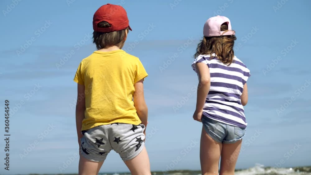 Boy and girl friends children play in shallow waterline of Baltic sea ...
